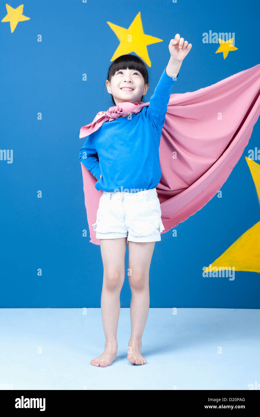 a girl posing like a superwoman with a pink cape around her neck Stock ...