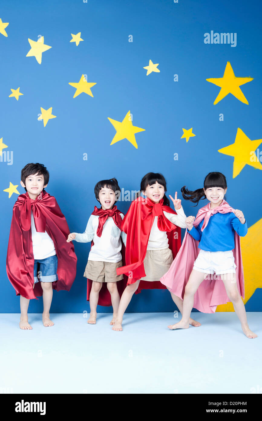 four kids wearing superman capes posing like superman Stock Photo - Alamy