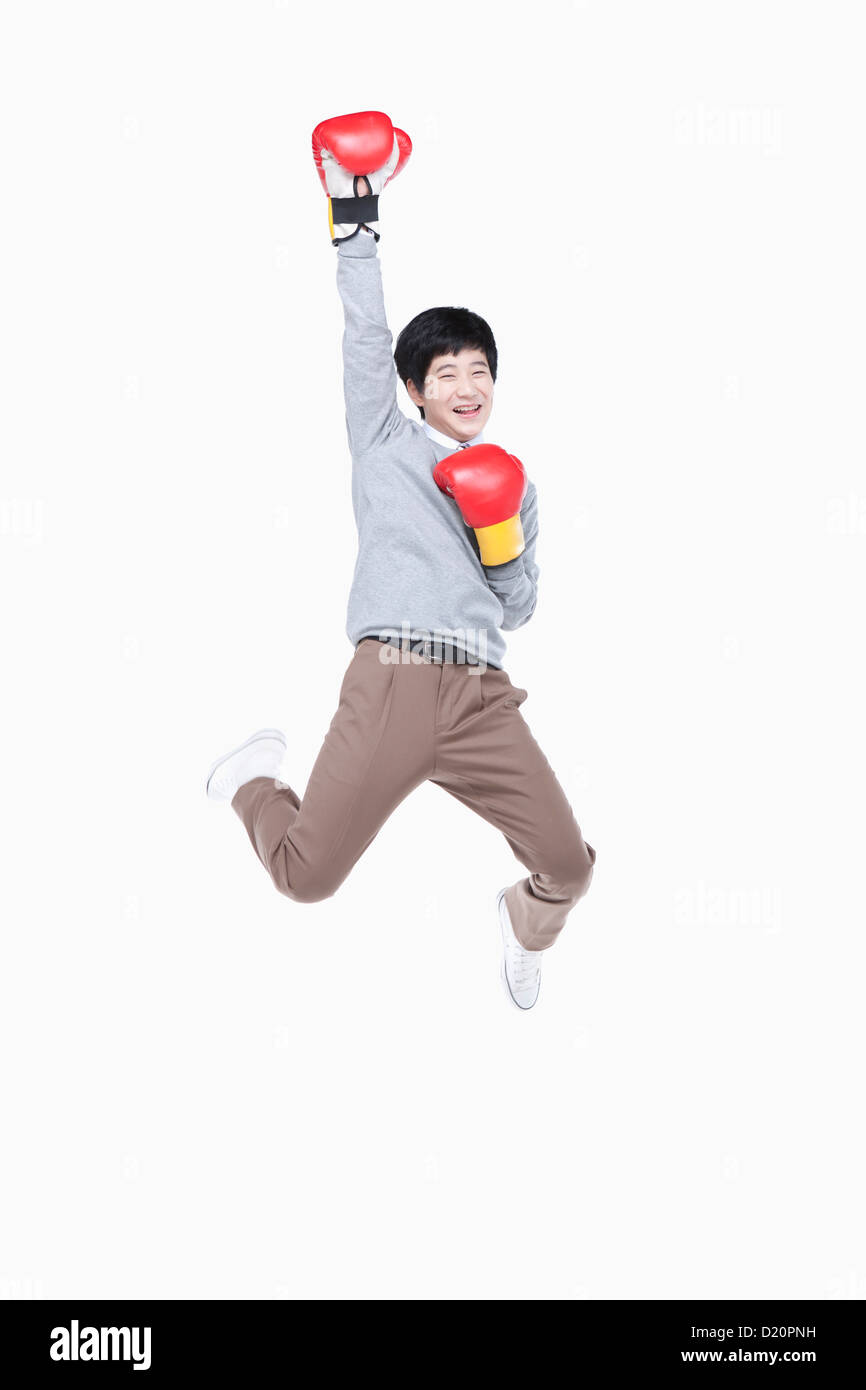 a male student with boxing gloves jumping while raising his arm up ...