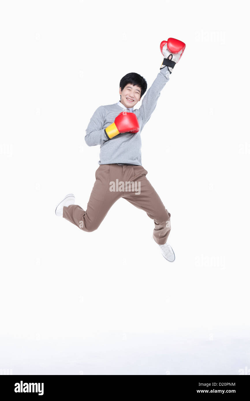 a male student with boxing gloves jumping while raising his arm up ...