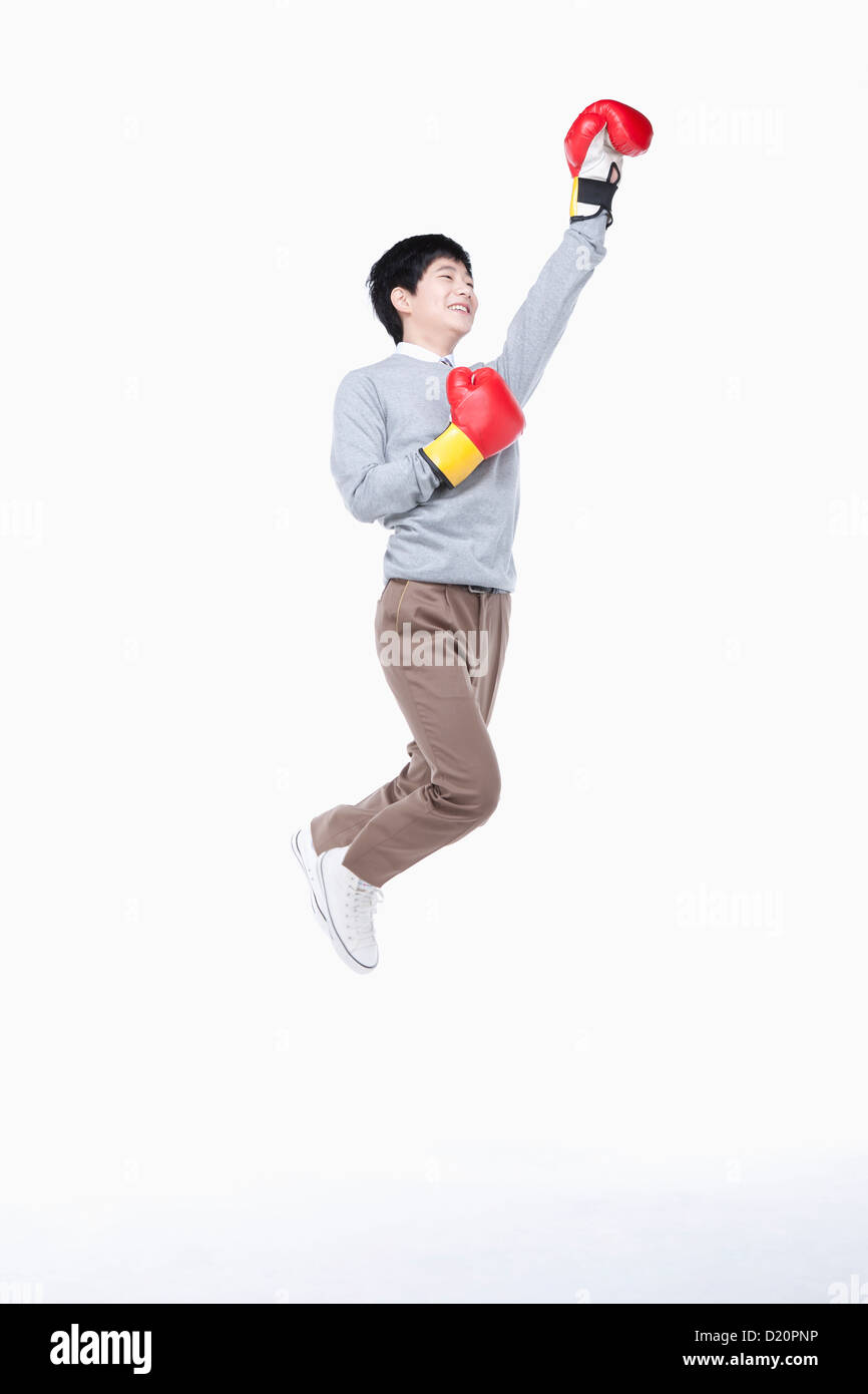 a male student with boxing gloves jumping while raising his arm up ...