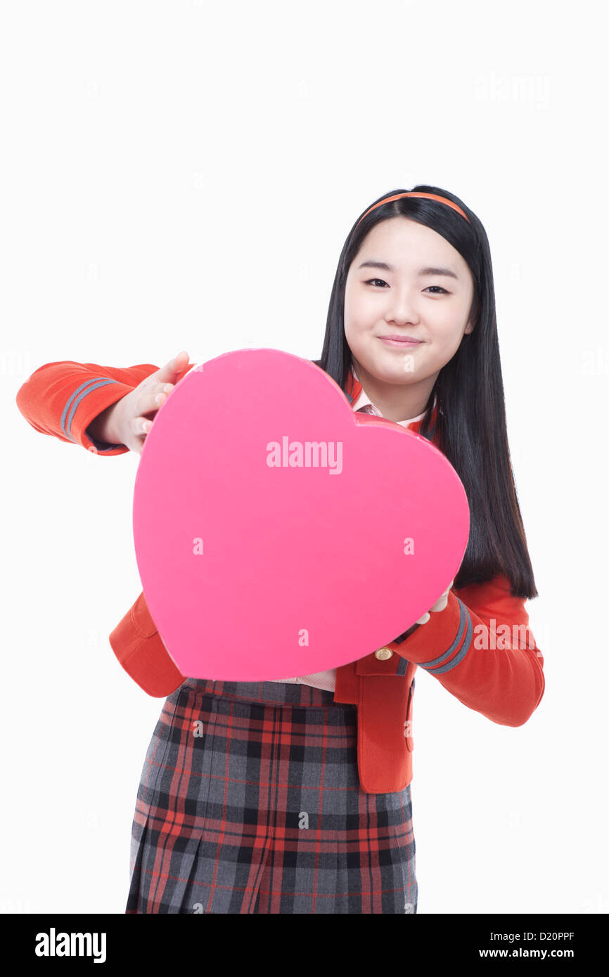 a female student holding a pink heart cushion smiling Stock Photo - Alamy