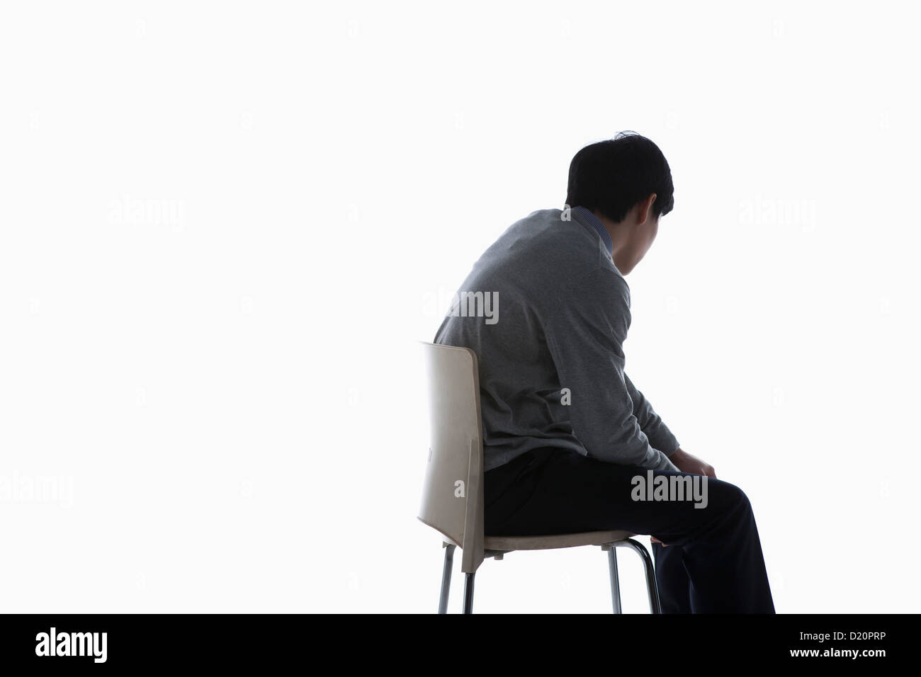 a male student sitting on a chair under a dark shadow Stock Photo - Alamy