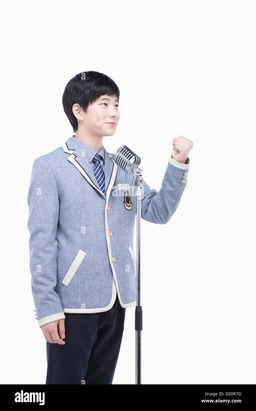 a male student standing behind a microphone stand with raising fist ...
