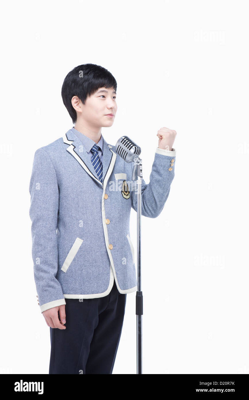 a male student standing behind a microphone stand with raising fist ...