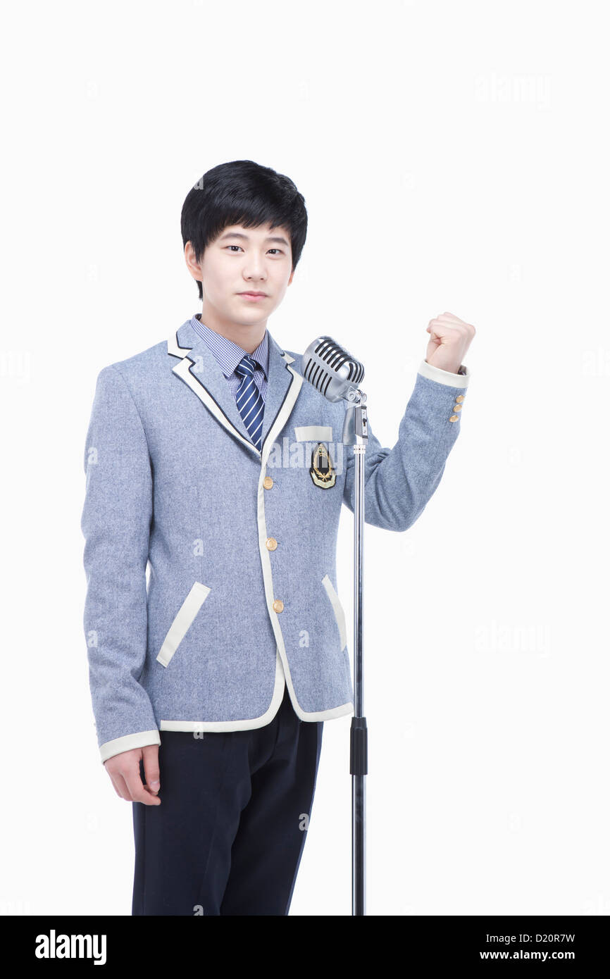 a male student standing behind a microphone stand with raising fist ...