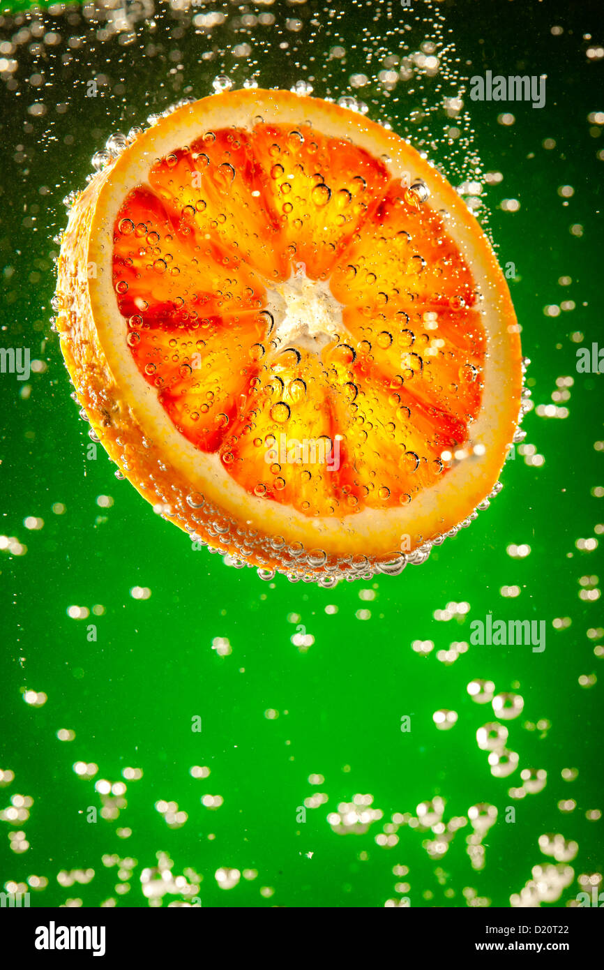 fresh red orange falls in water on a green background Stock Photo - Alamy