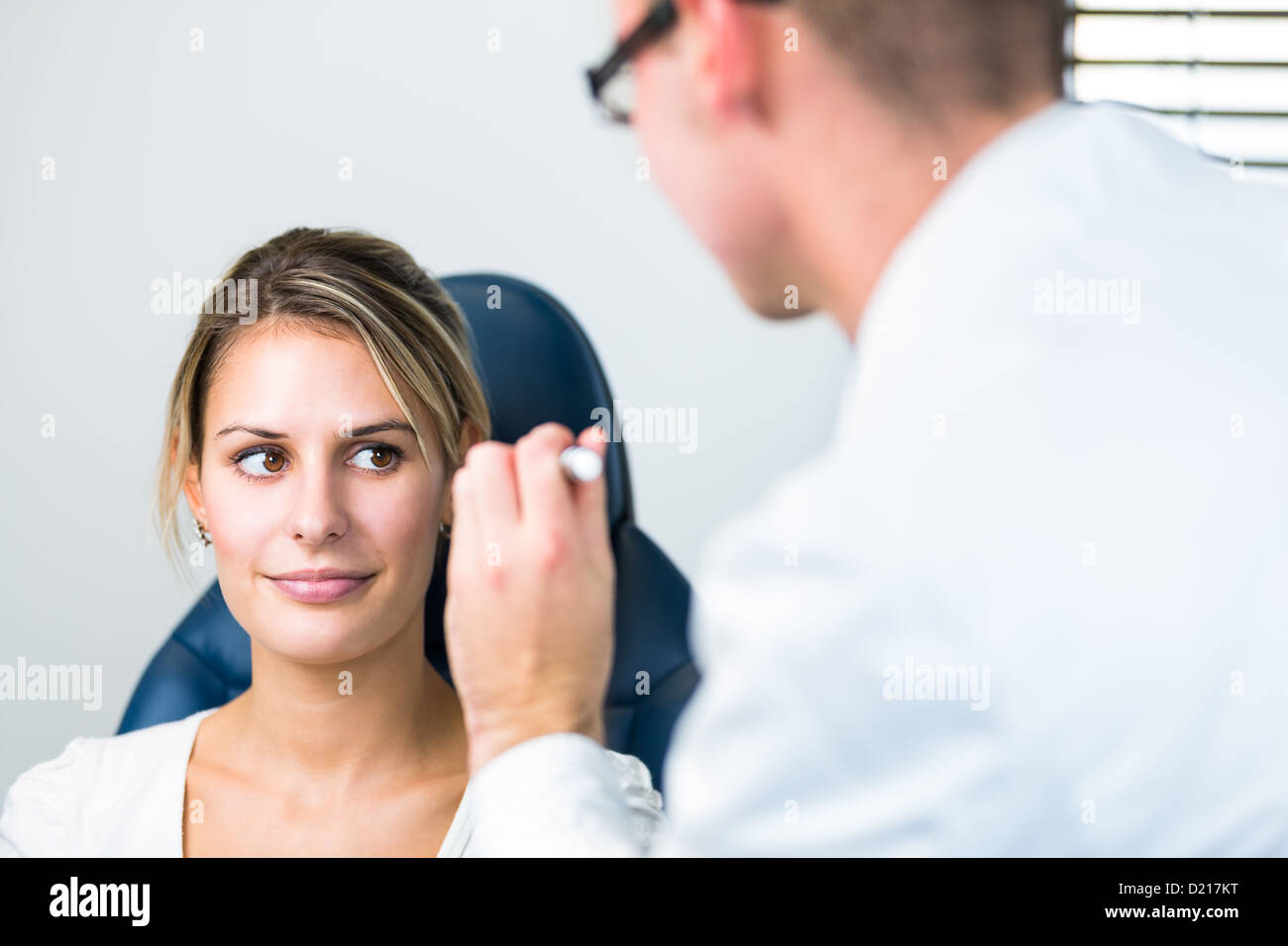 Optometry concept - pretty young woman having her eyes examined by an ...