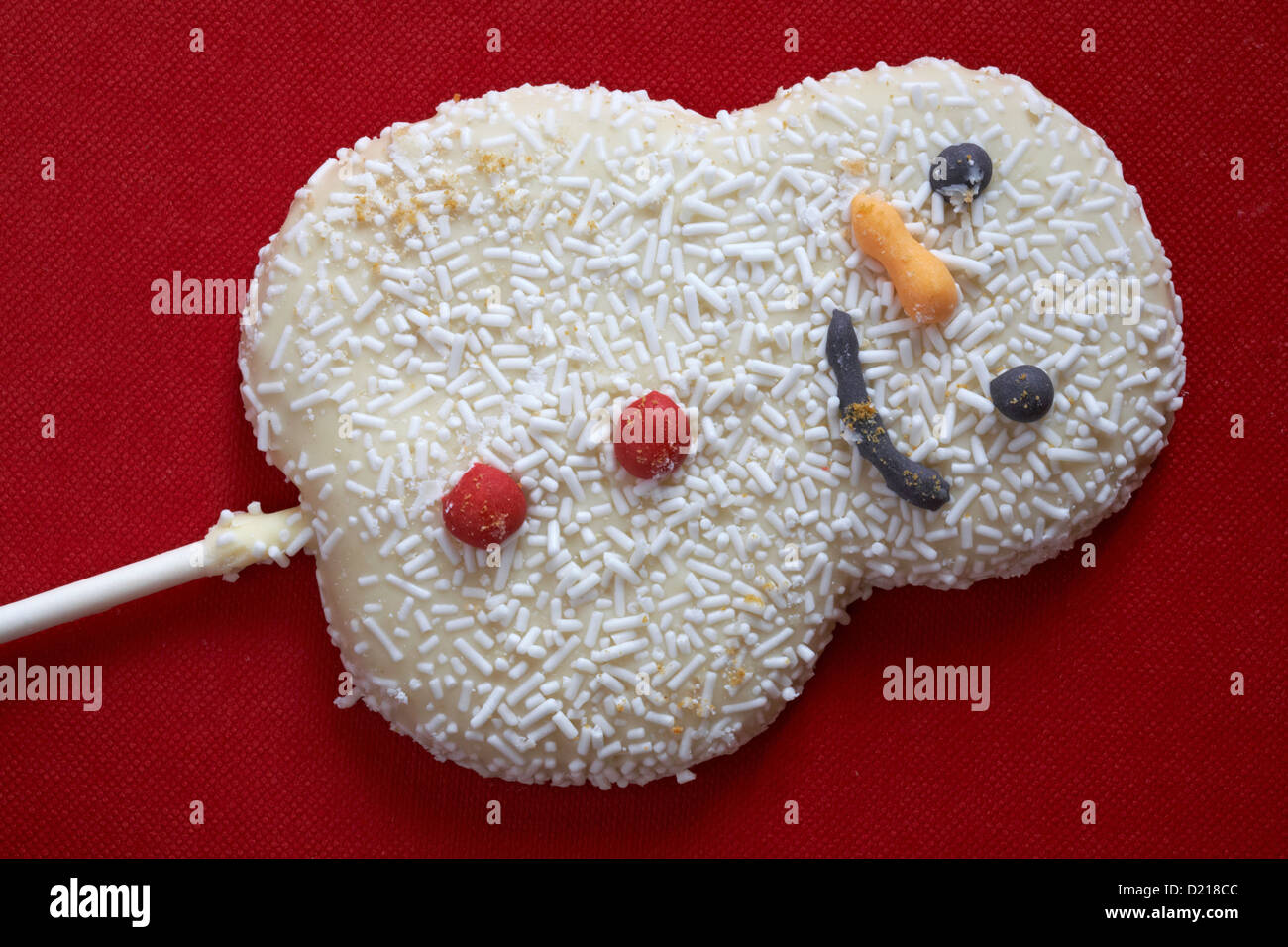 Snowman biscuit lolly on stick set against red background Stock Photo ...
