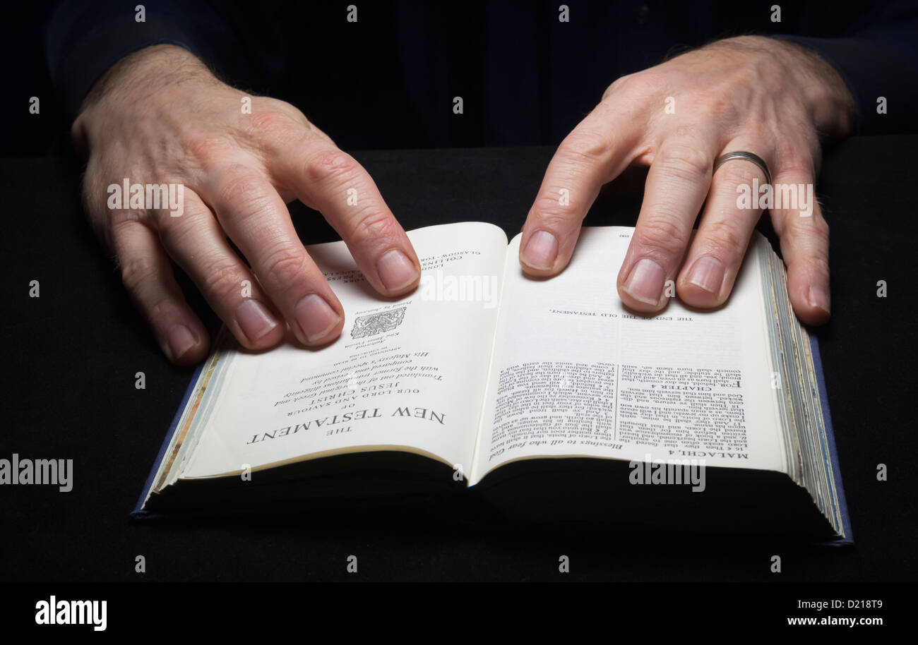 A man reading the Holy Bible with two hands Stock Photo - Alamy