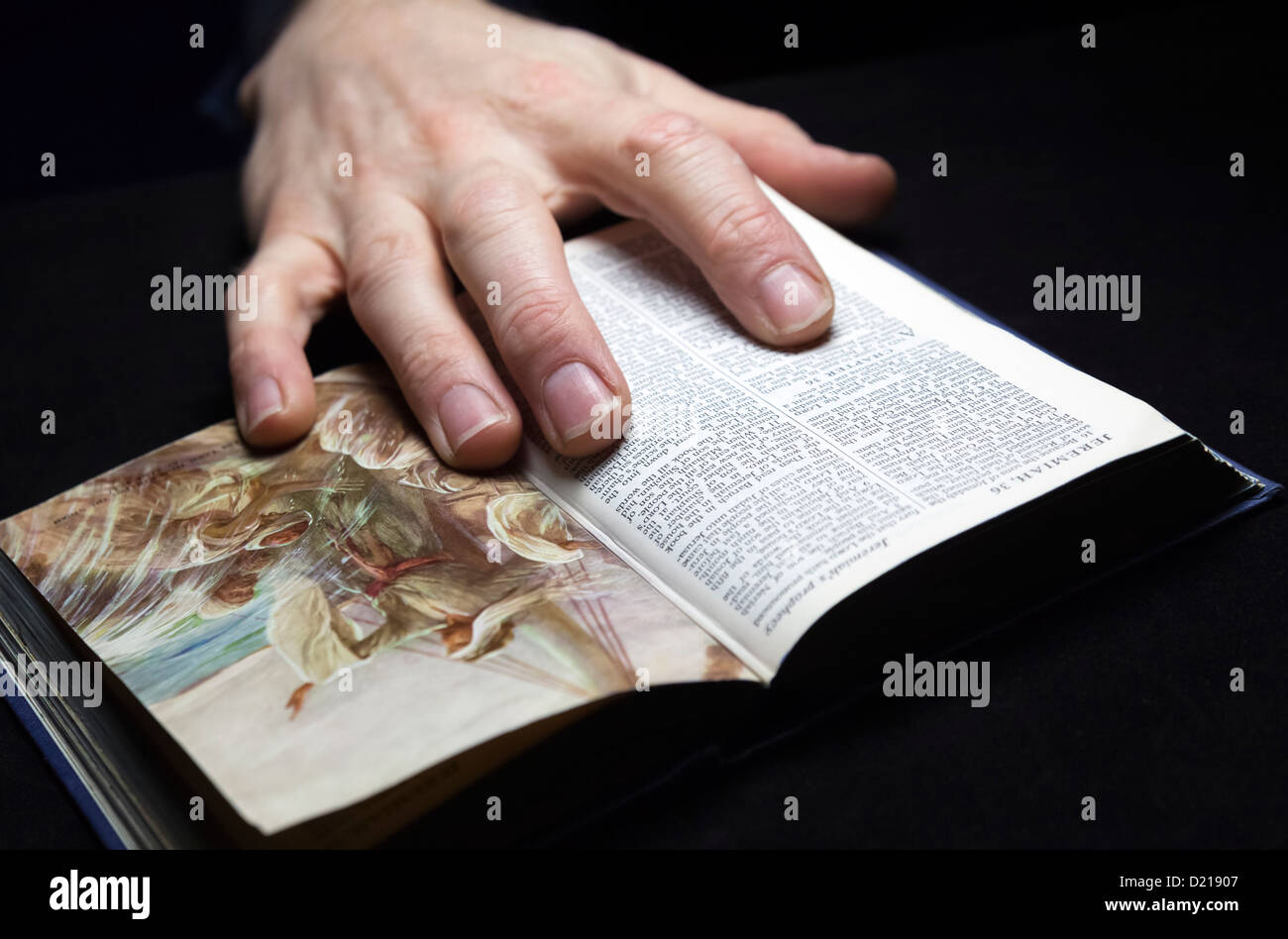 A man reading the Holy Bible with one hand Stock Photo - Alamy