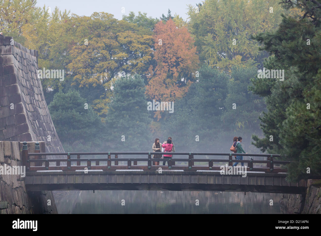 People walking on a stone bridge over the moat of the old palace in ...