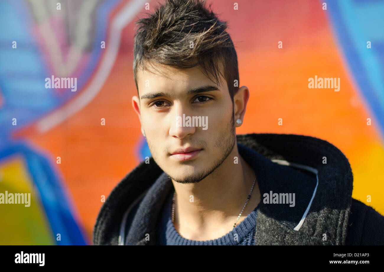 Handsome young man against colorful graffiti covered wall Stock Photo ...