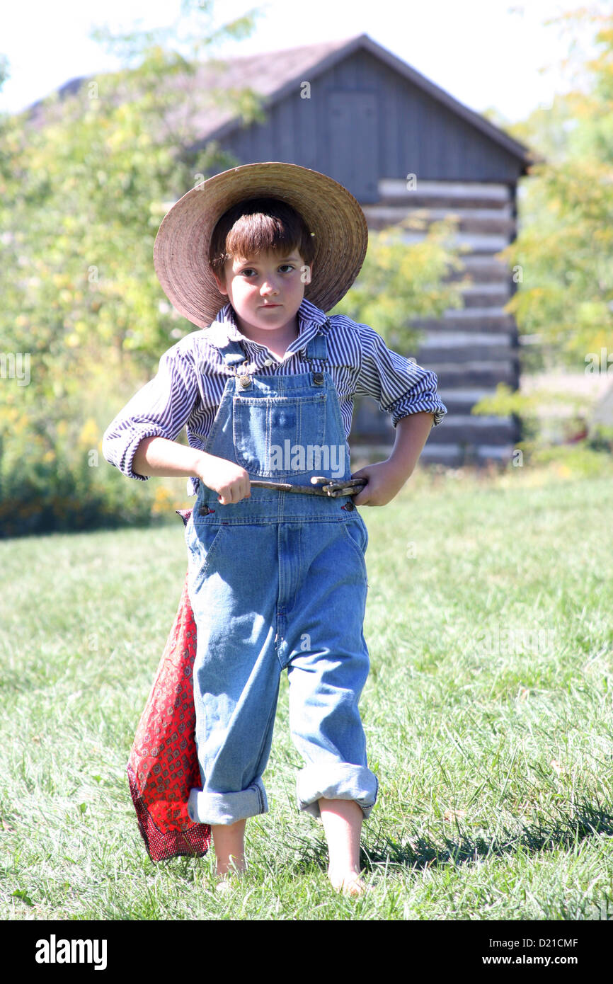 A little farmer boy playing with sticks by a log cabin Stock Photo - Alamy