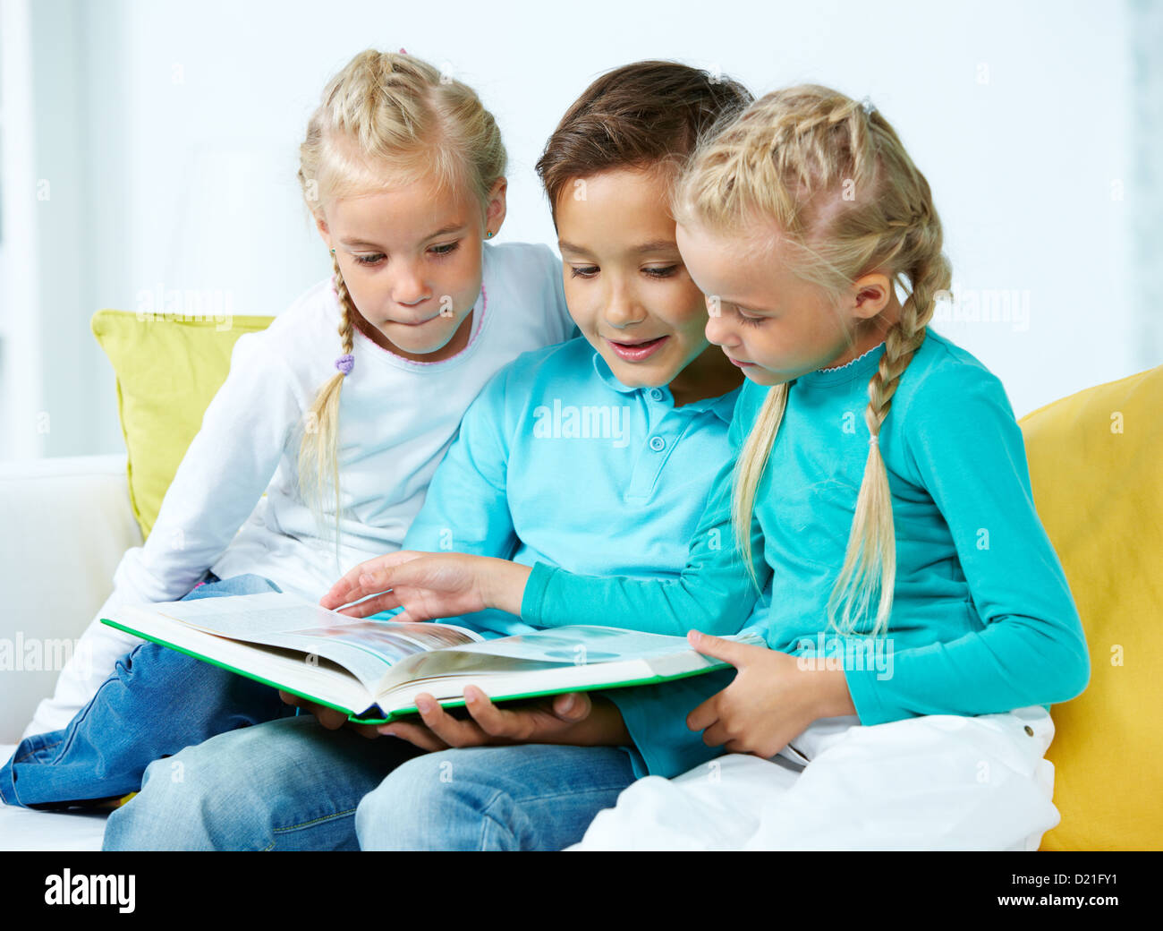 Lovely children looking through a picture book Stock Photo - Alamy