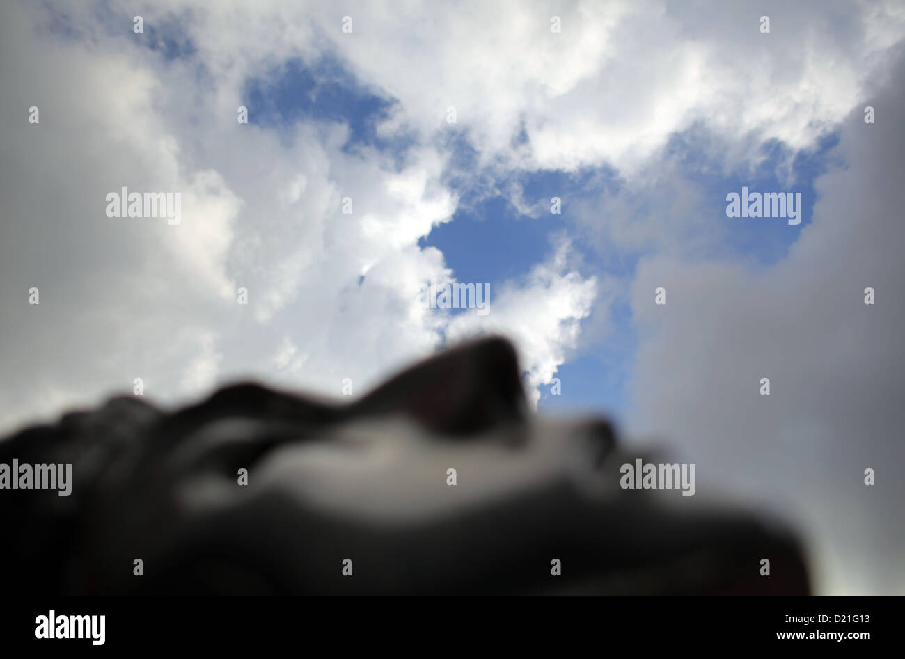 The clouds break apart behind a sculpture by Thomas Schuette in Cologne ...