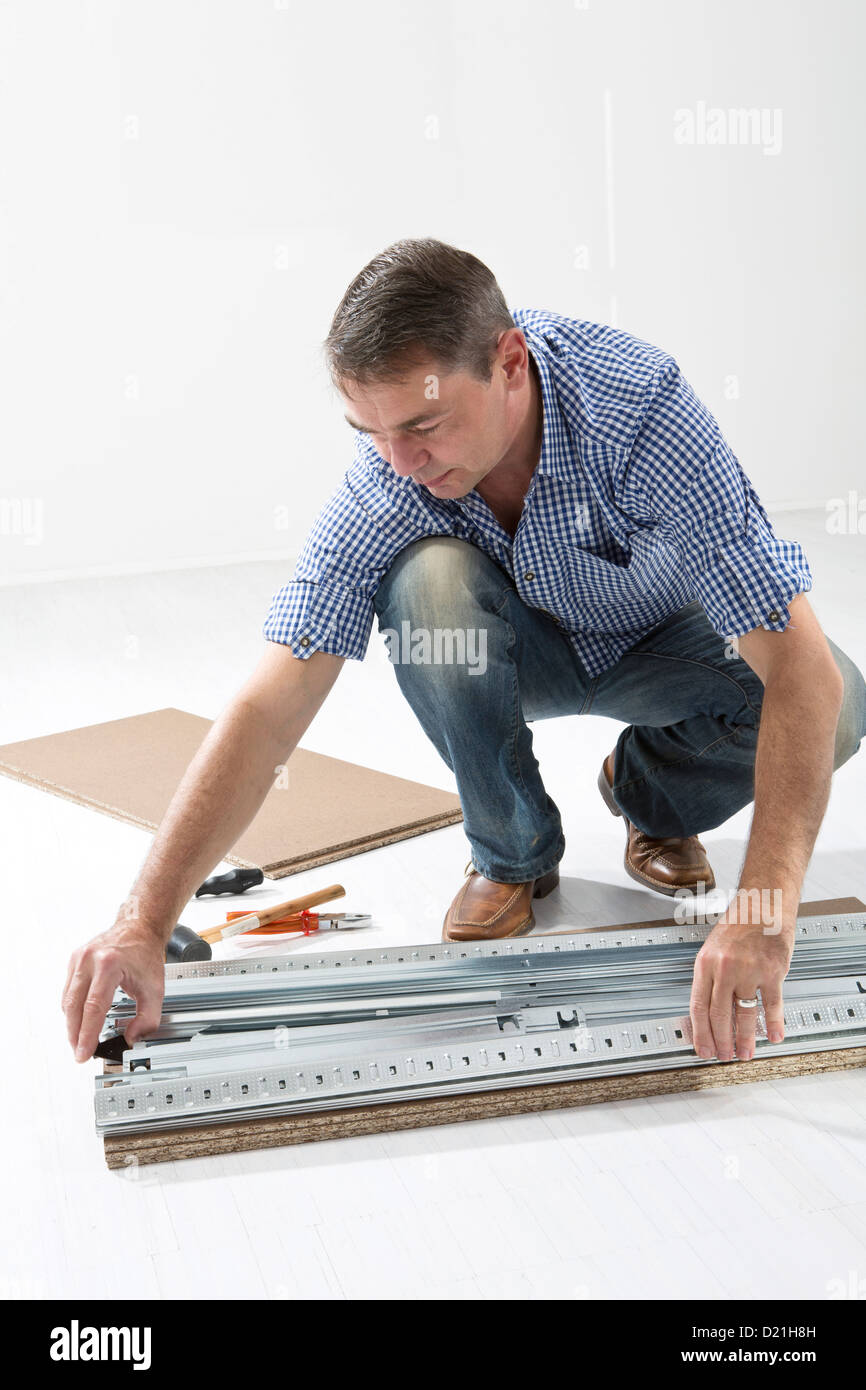 Mature man building shelf Stock Photo - Alamy