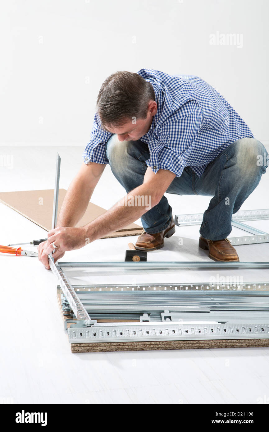 Mature man building shelf Stock Photo - Alamy