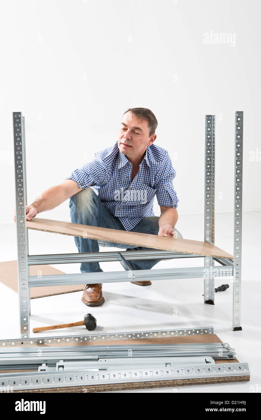 Mature man building shelf Stock Photo - Alamy