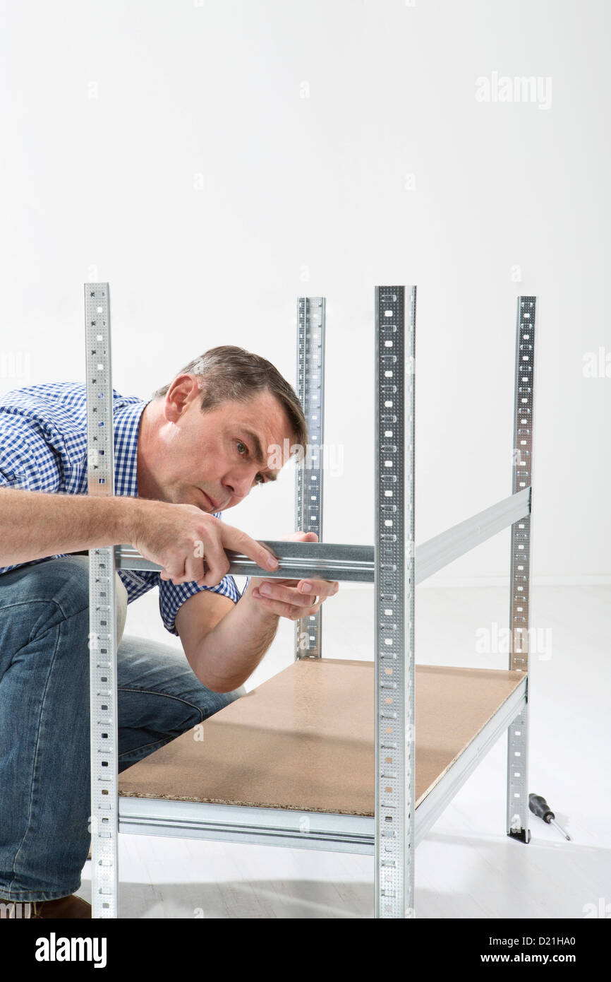 Mature man building shelf Stock Photo - Alamy
