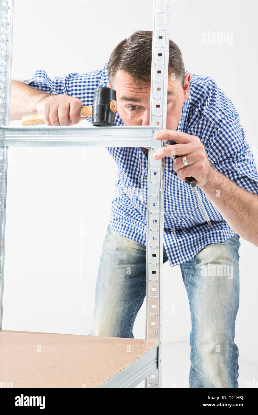 Mature man building shelf Stock Photo - Alamy