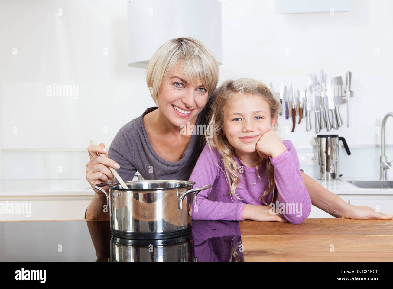 Germany, Bavaria, Munich, Mother and daughter preparing food, smiling ...
