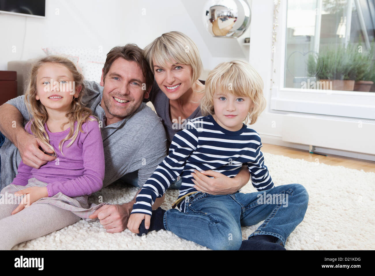 Germany, Bavaria, Munich, Portrait of family lying on floor, smiling ...