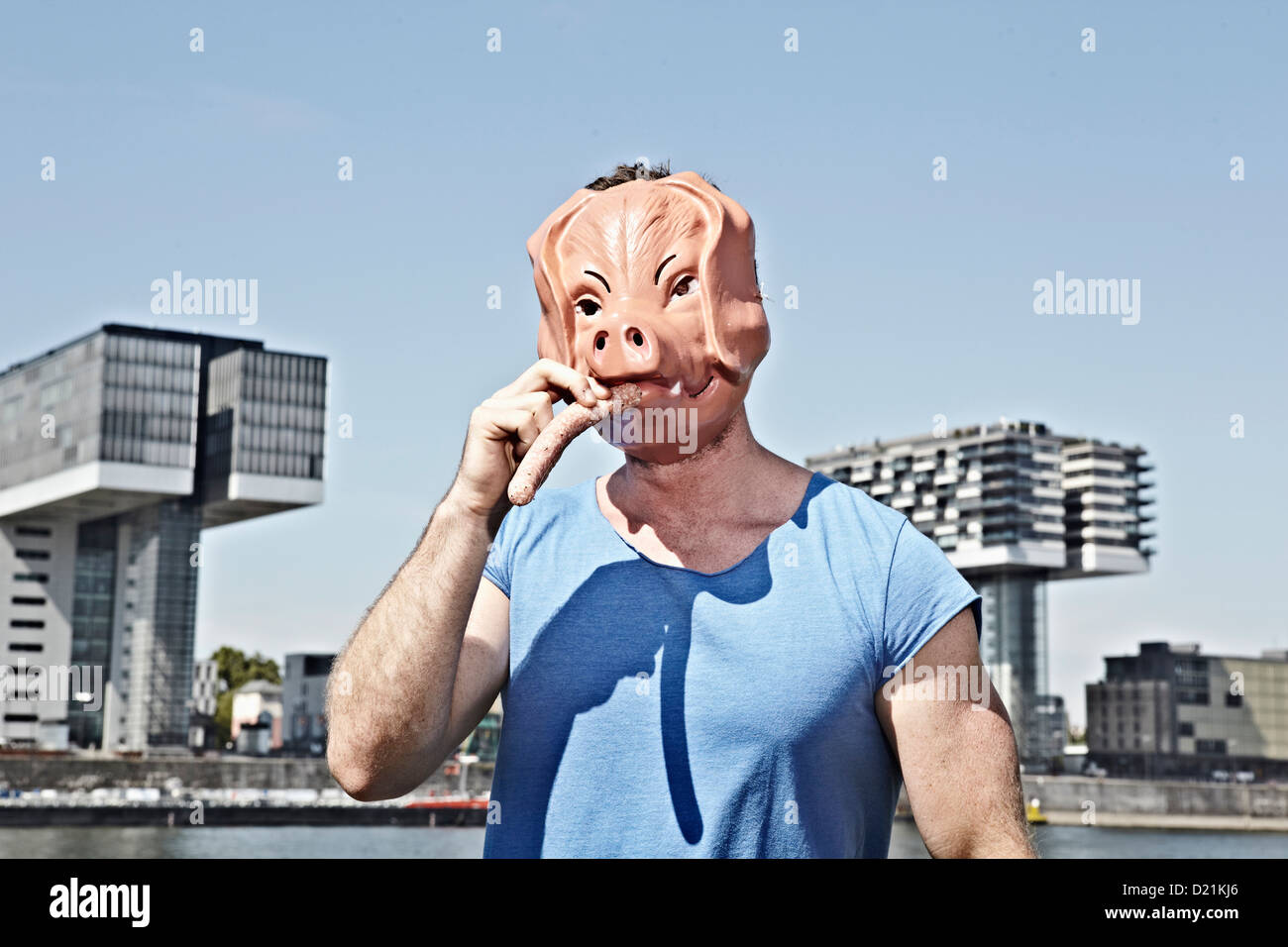 Germany, Cologne, Young man with pig mask eating sausage Stock Photo ...