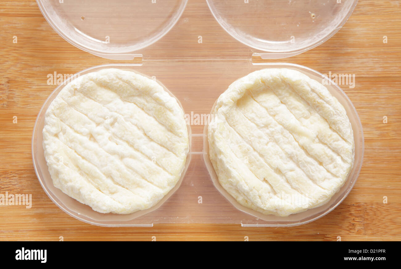 Two rounds of Saint-Marcellin French cheese in a container on a ...