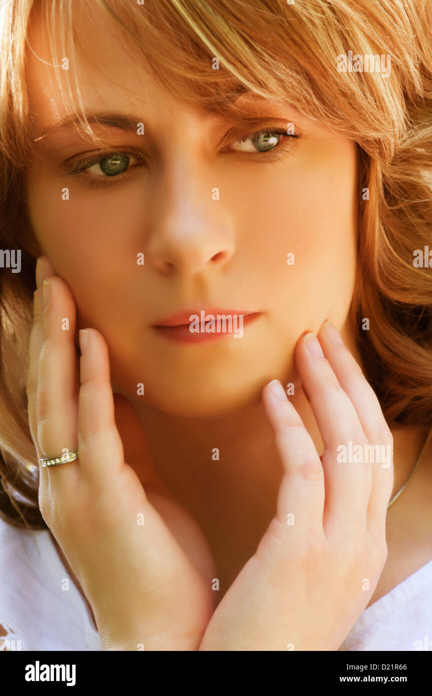 Beautiful young woman hands touching face looking away Stock Photo - Alamy