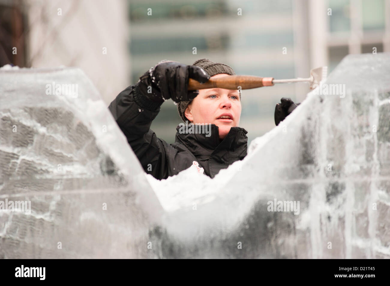 London, UK - 11 January 2012: a sculptor works a block of ice with his ...