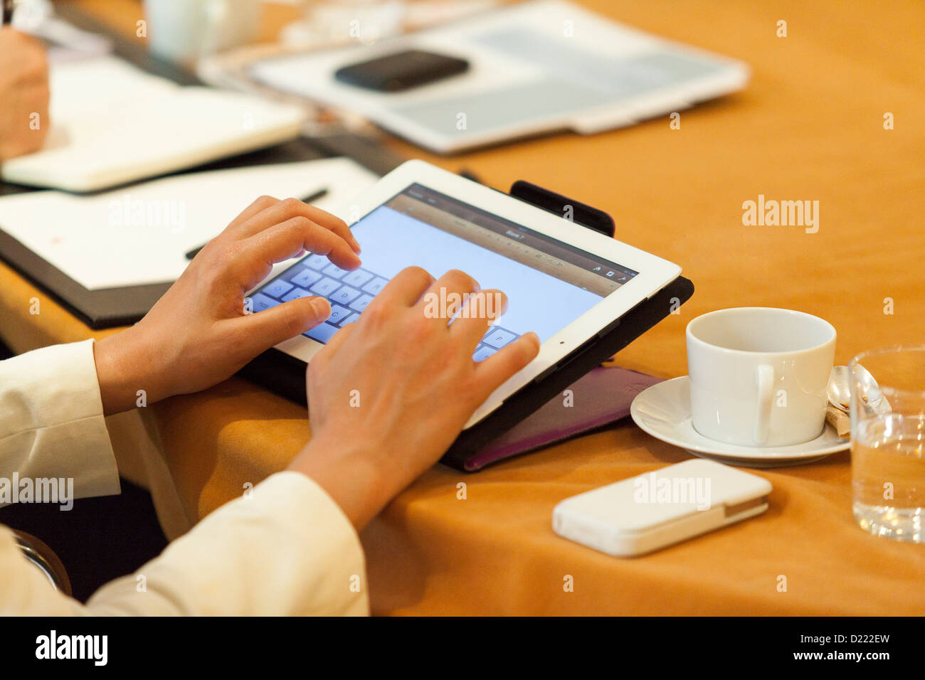 Person typing on a tablet during a business meeting Stock Photo - Alamy