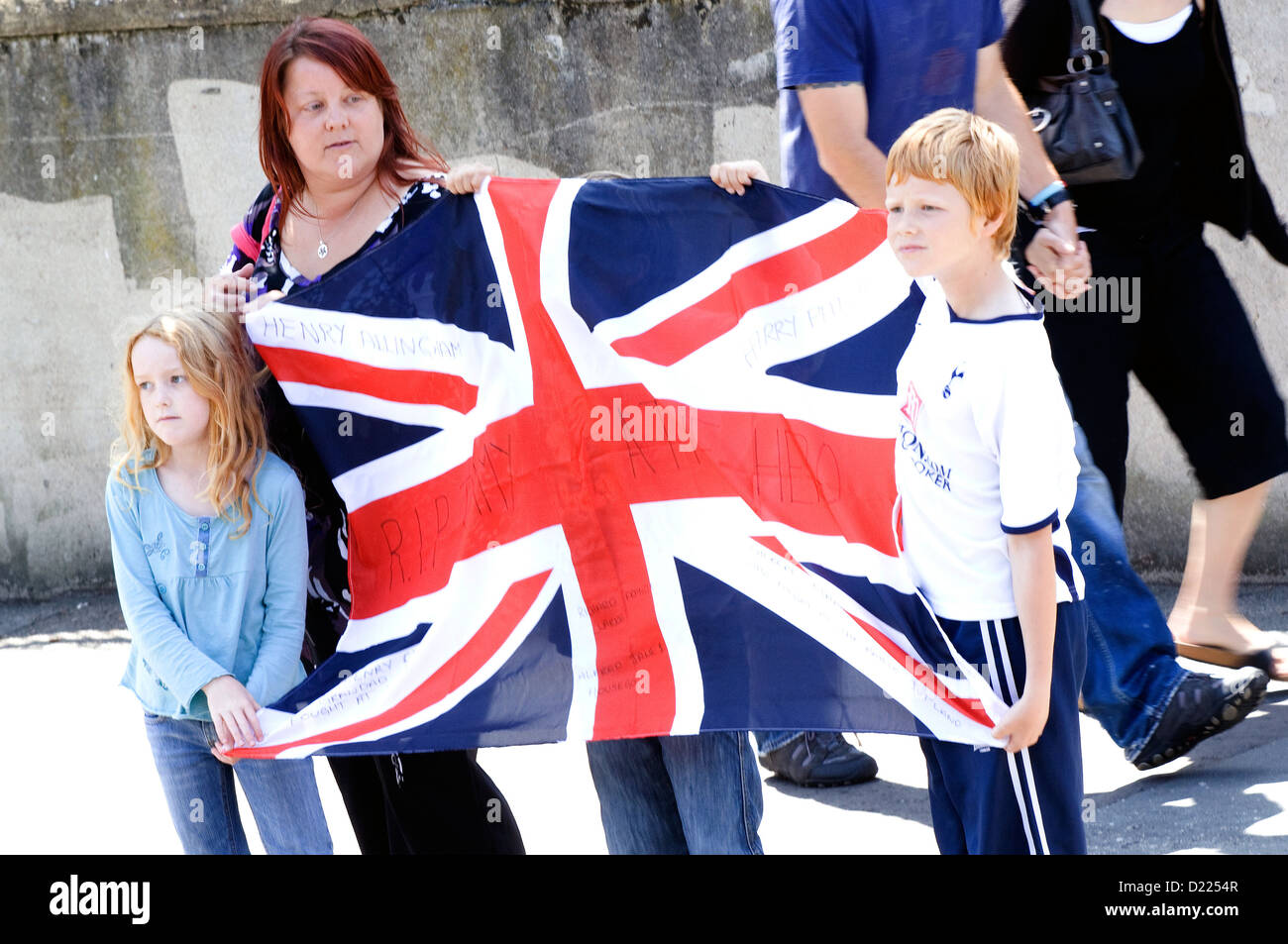 A family holds up the Union Jack flag at a military funeral in the UK ...