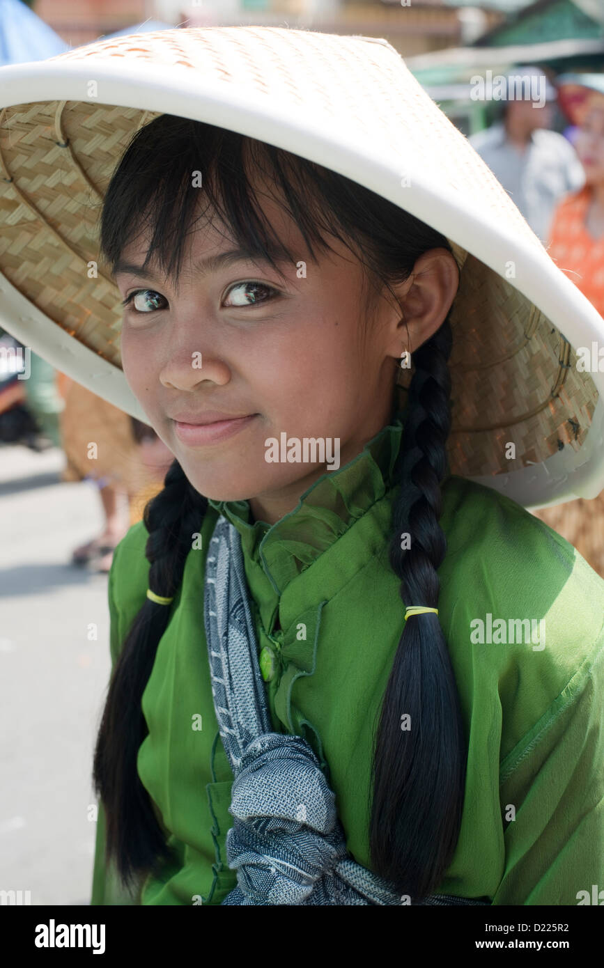 A participant, wearing a traditional conical hat, smiles during a ...