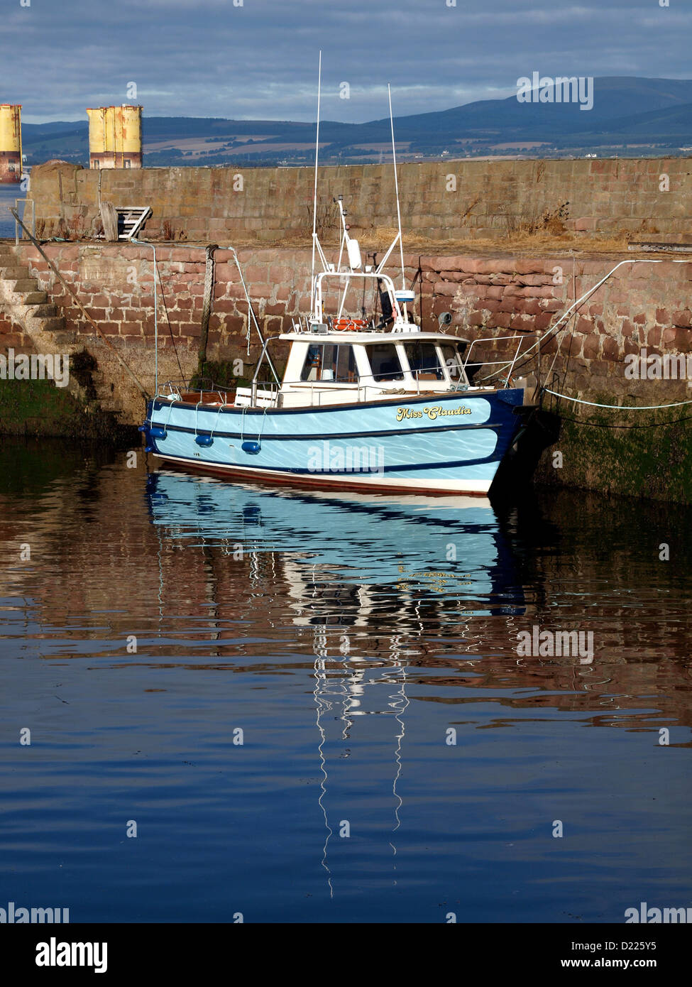 A small fishing boat is reflected in the still waters of the historic ...