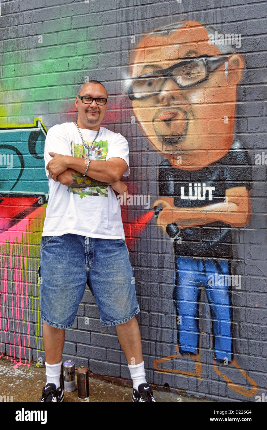 Portrait of a graffiti artist in front of his self portrait at 5 Pointz ...