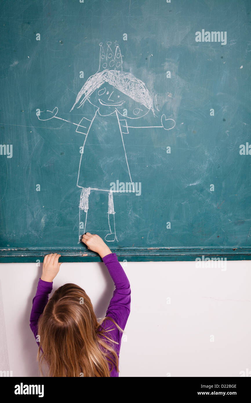 Studio portrait of young girl in classroom drawing image of princess ...