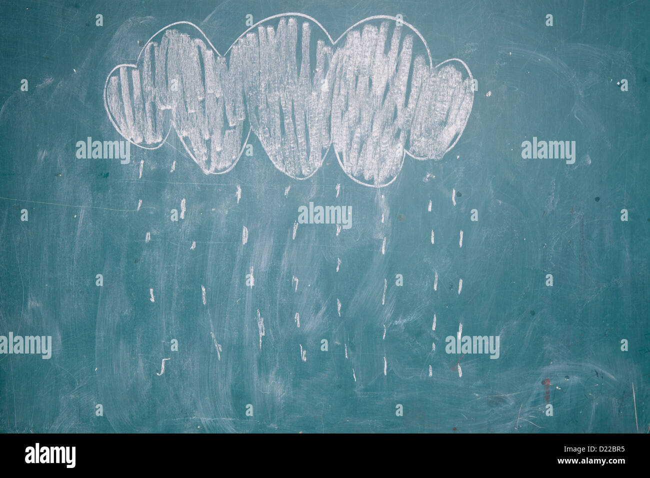 Chalk drawing by young child on chalkboard of rain cloud with raindrops ...
