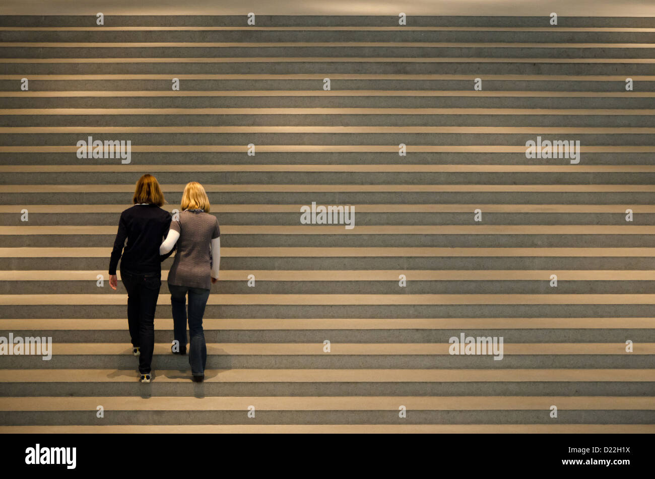 back view of two women arm in arm walking up stairs Stock Photo - Alamy