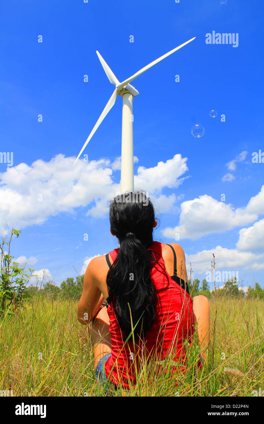 pretty young woman looking at a windmill/wind turbine turning in the ...