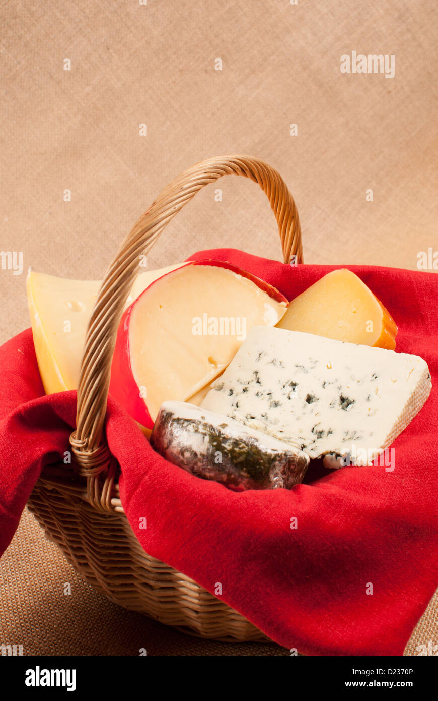 Still life of assorted cheese varieties inside a traditional basket ...