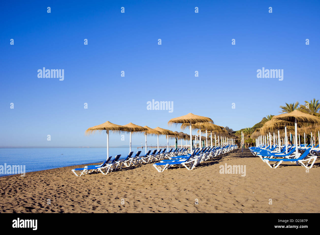 Sun loungers on a tranquil beach at the popular resort city of Marbella ...