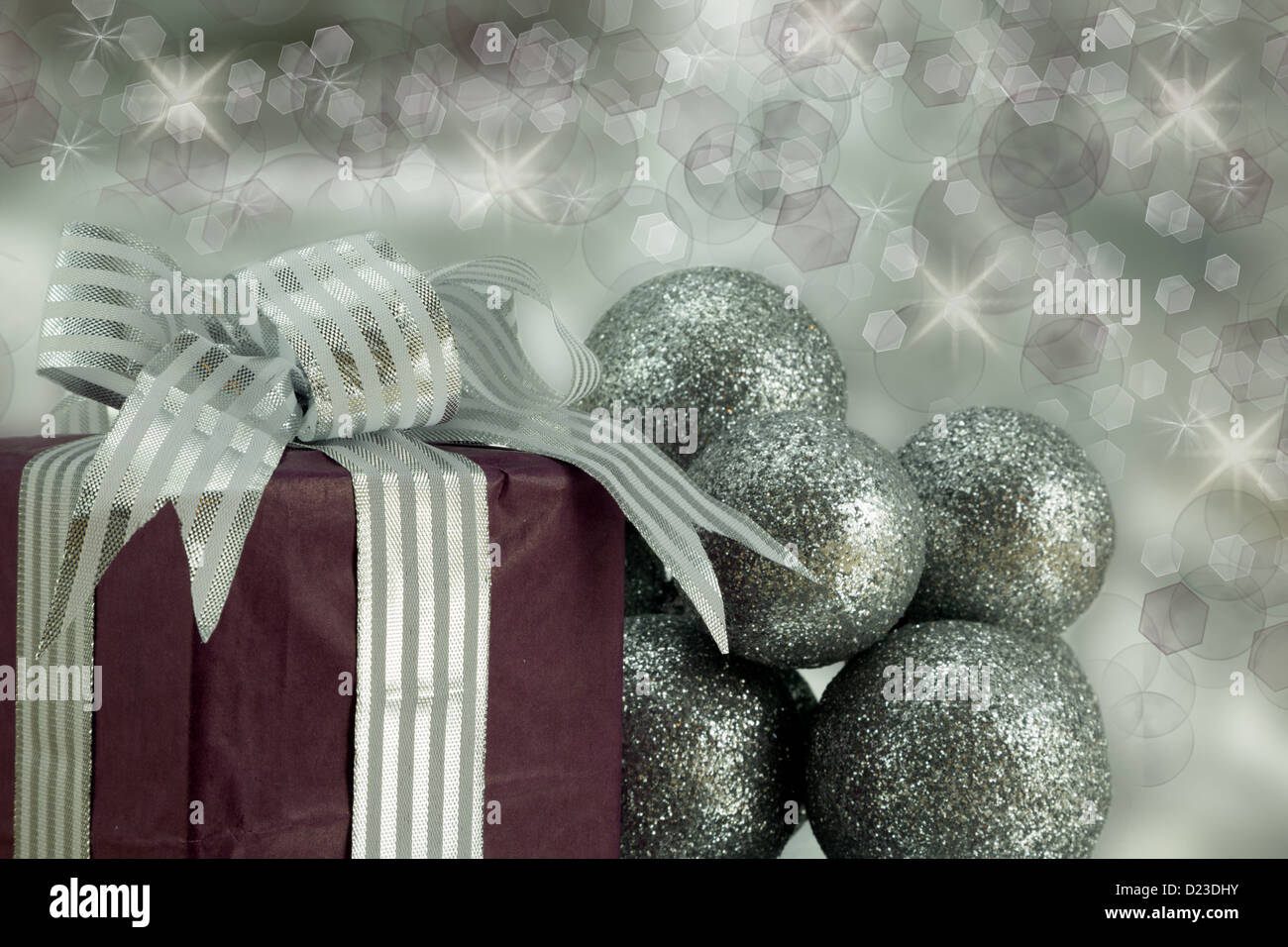 Wrapped present with silver baubles and diffused sparkle background ...