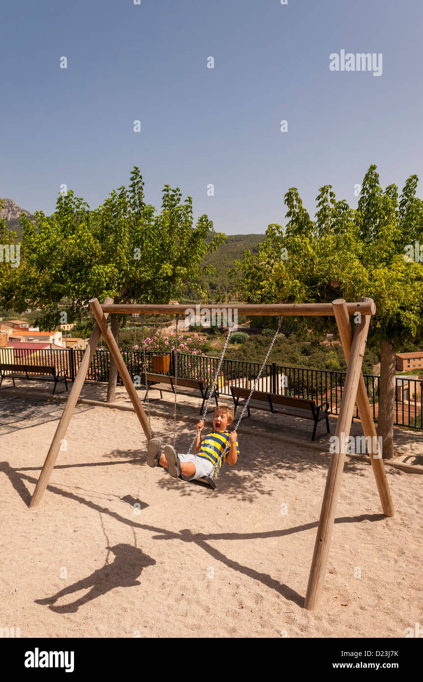 A boy playing on a swing in the old village of Pratdip , Costa Dorada ...