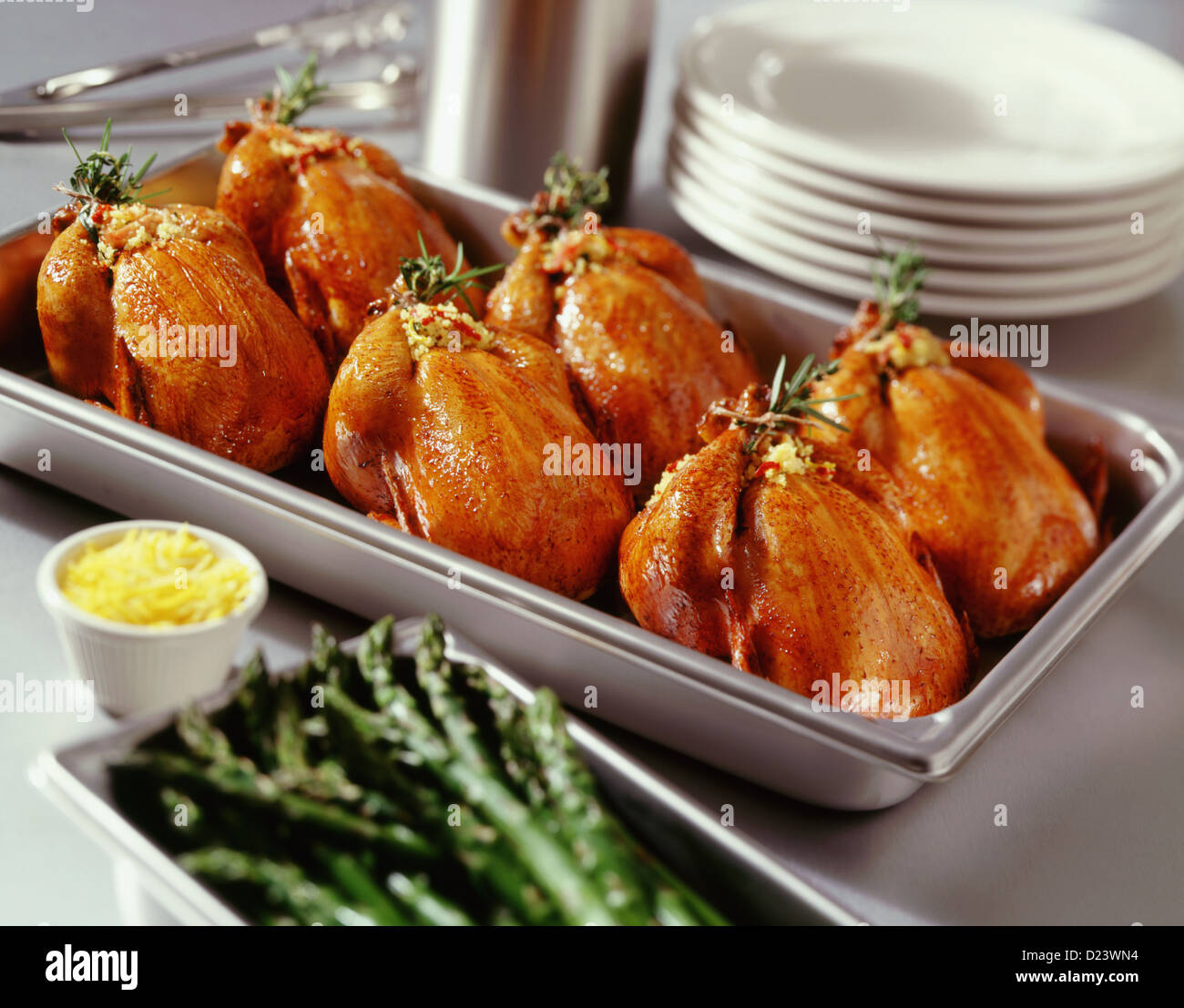 Roasted game hens in a cooking pan with asparagus in a kitchen ...