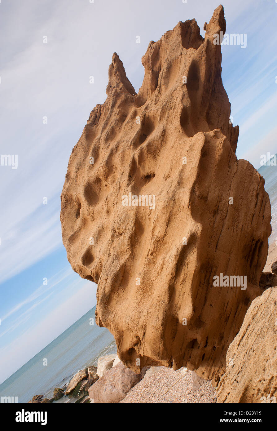 large boulder on a calm beach. very slanted horizon with erect boulder ...