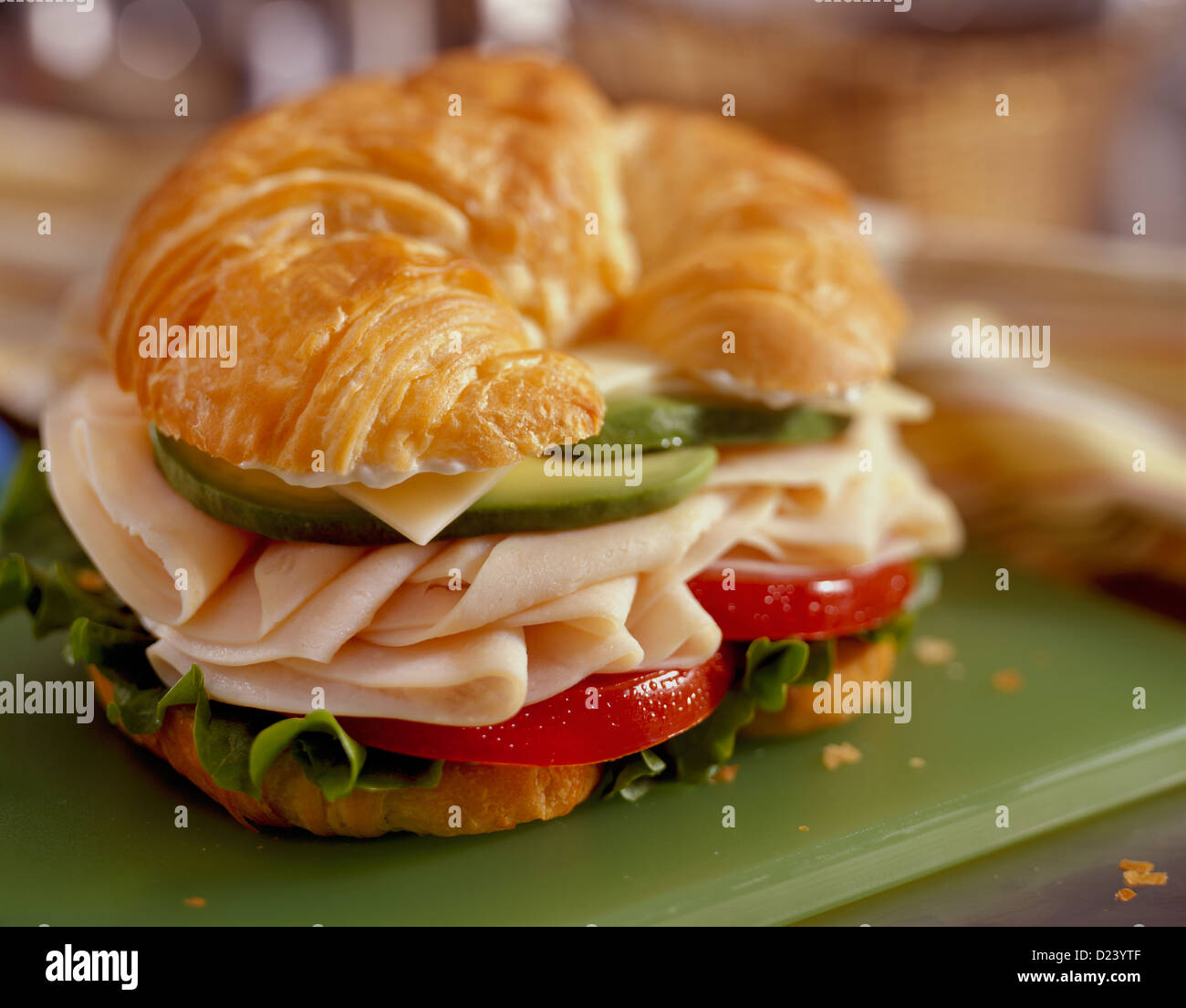 Croissant sandwich with turkey, tomato, cheese and avocado on a cutting ...
