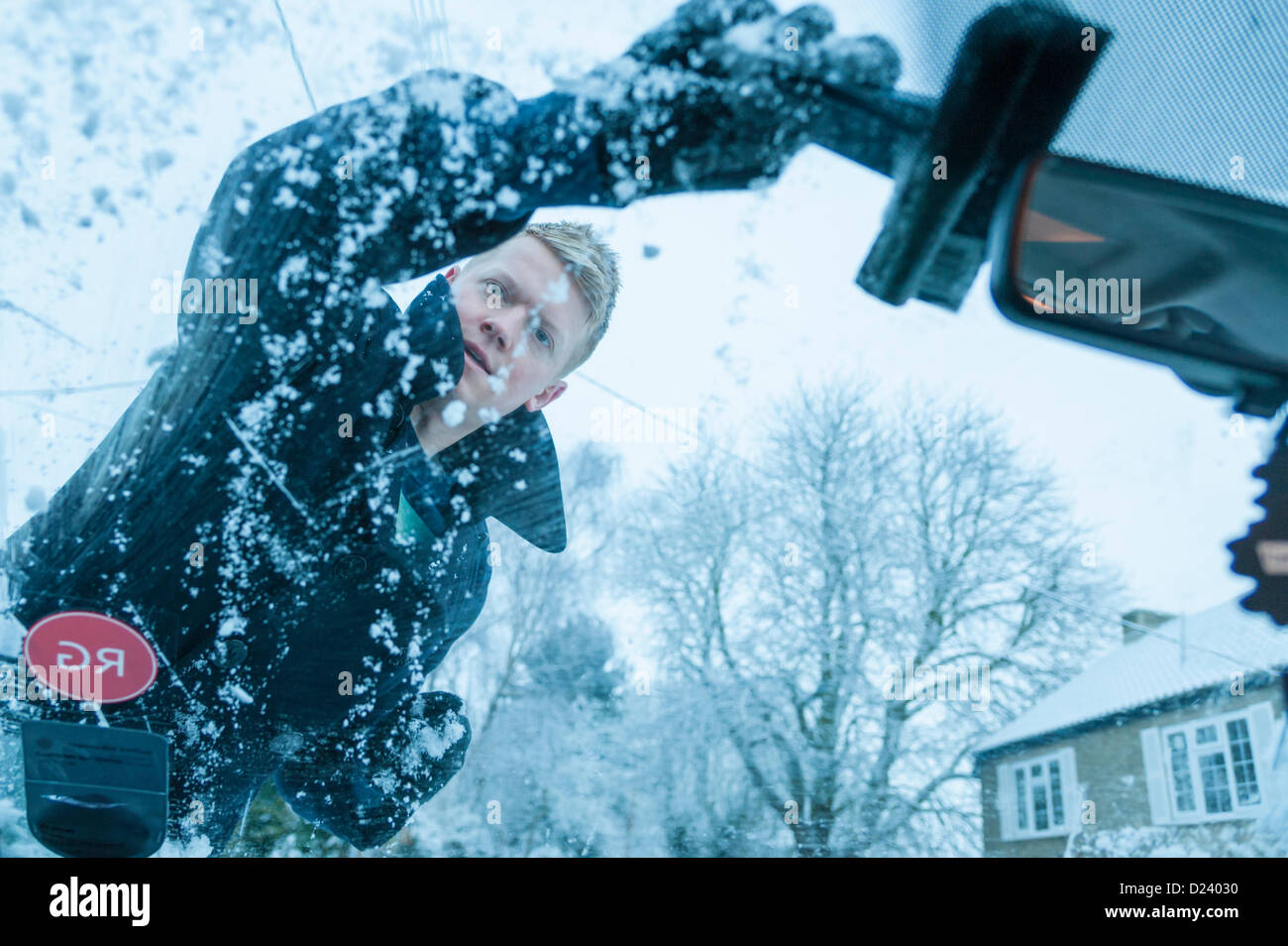 Cambridge, UK. 14th January 2013. Joe Gilson scrapes the overnight snow ...