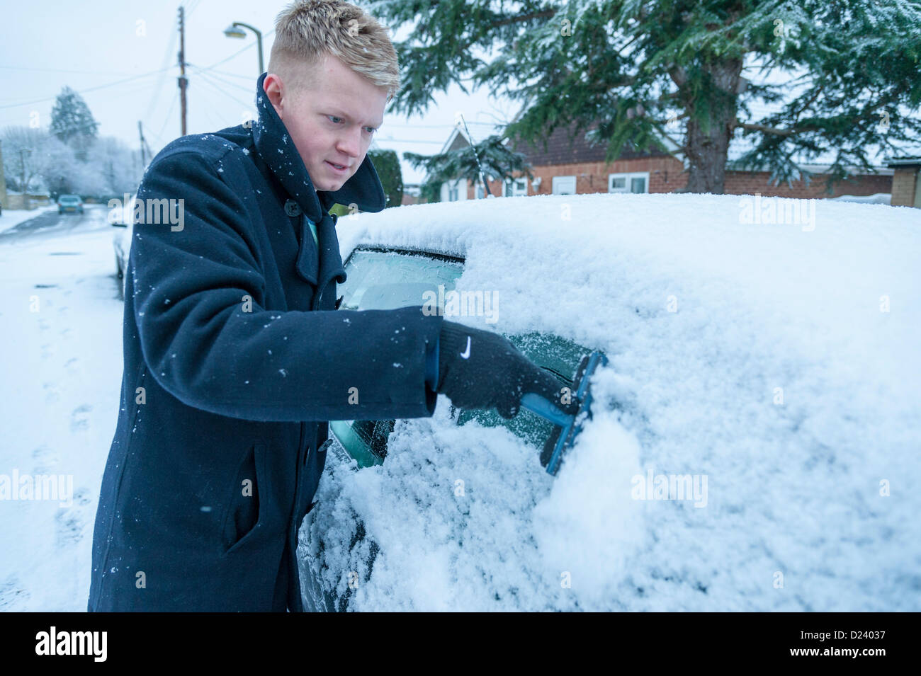 Cambridge, UK. 14th January 2013. Joe Gilson scrapes the overnight snow ...