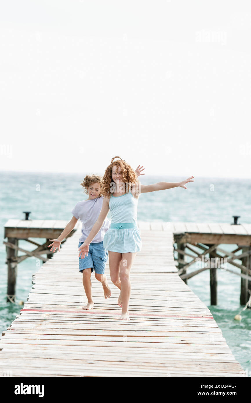 Spain, Girl and boy running on jetty at he sea Stock Photo - Alamy